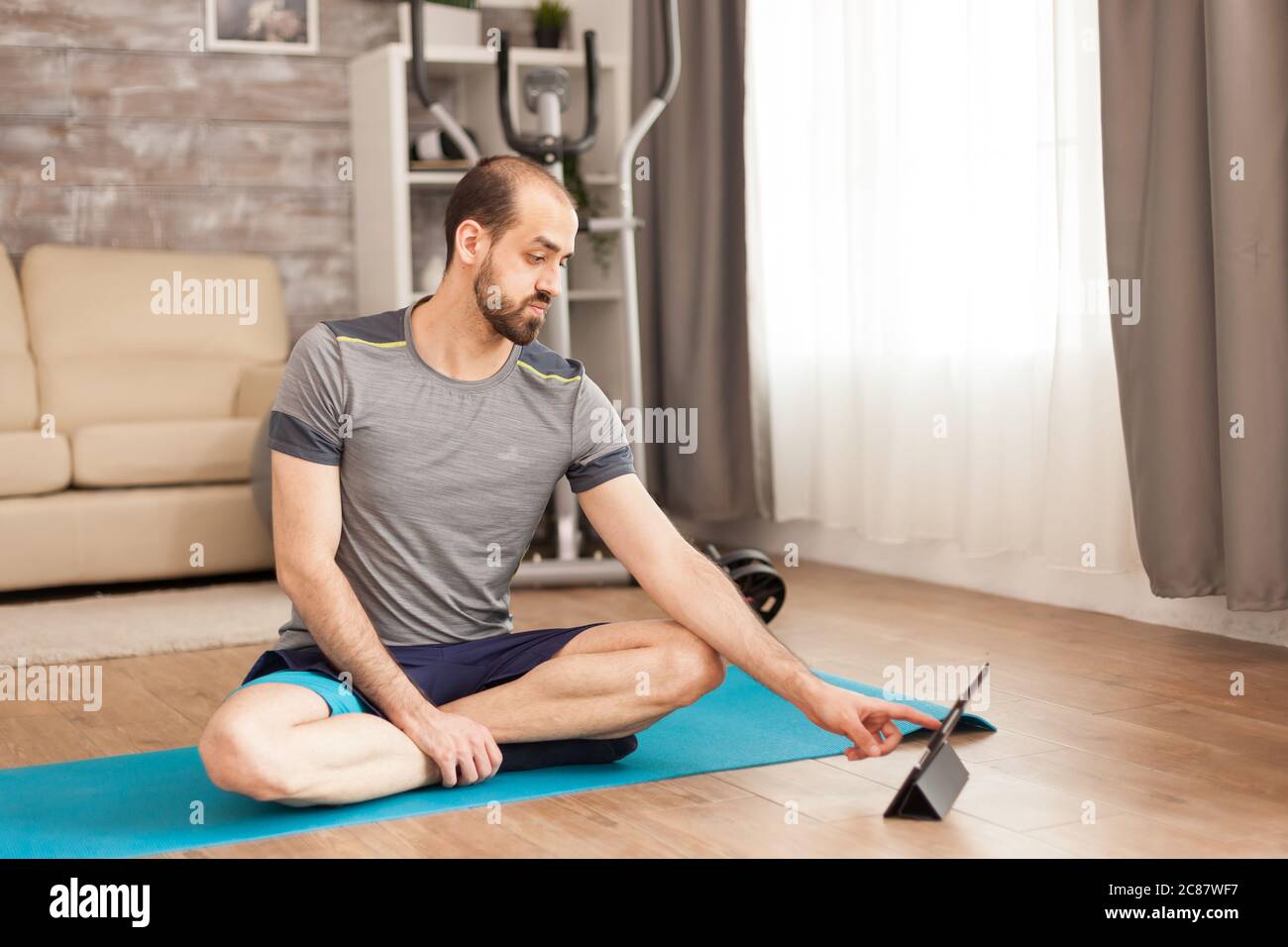 Happy man with healthy lifestyle watching yoga class on tablet computer ...