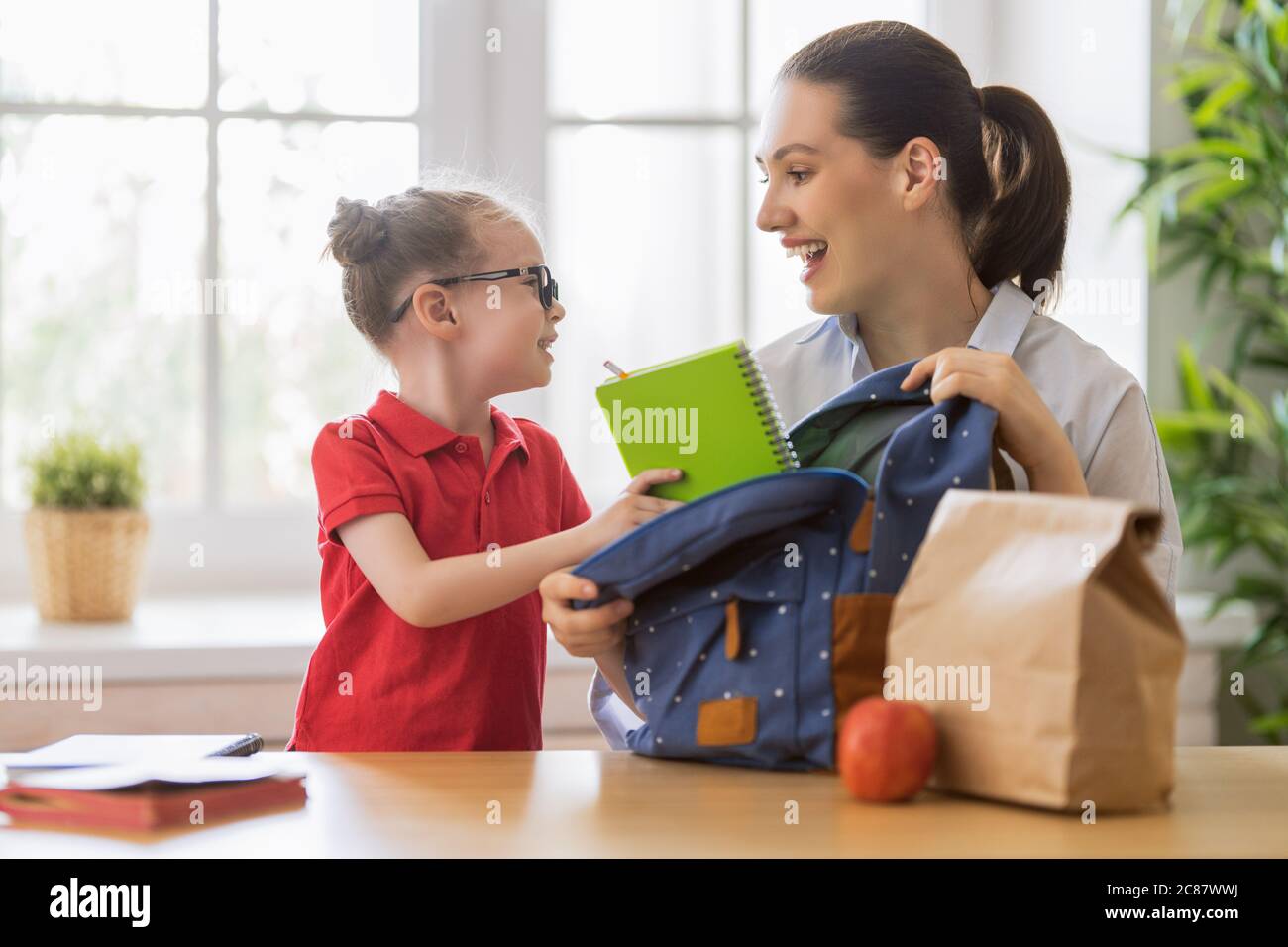 Happy family preparing for school. Little girl with mother putting ...
