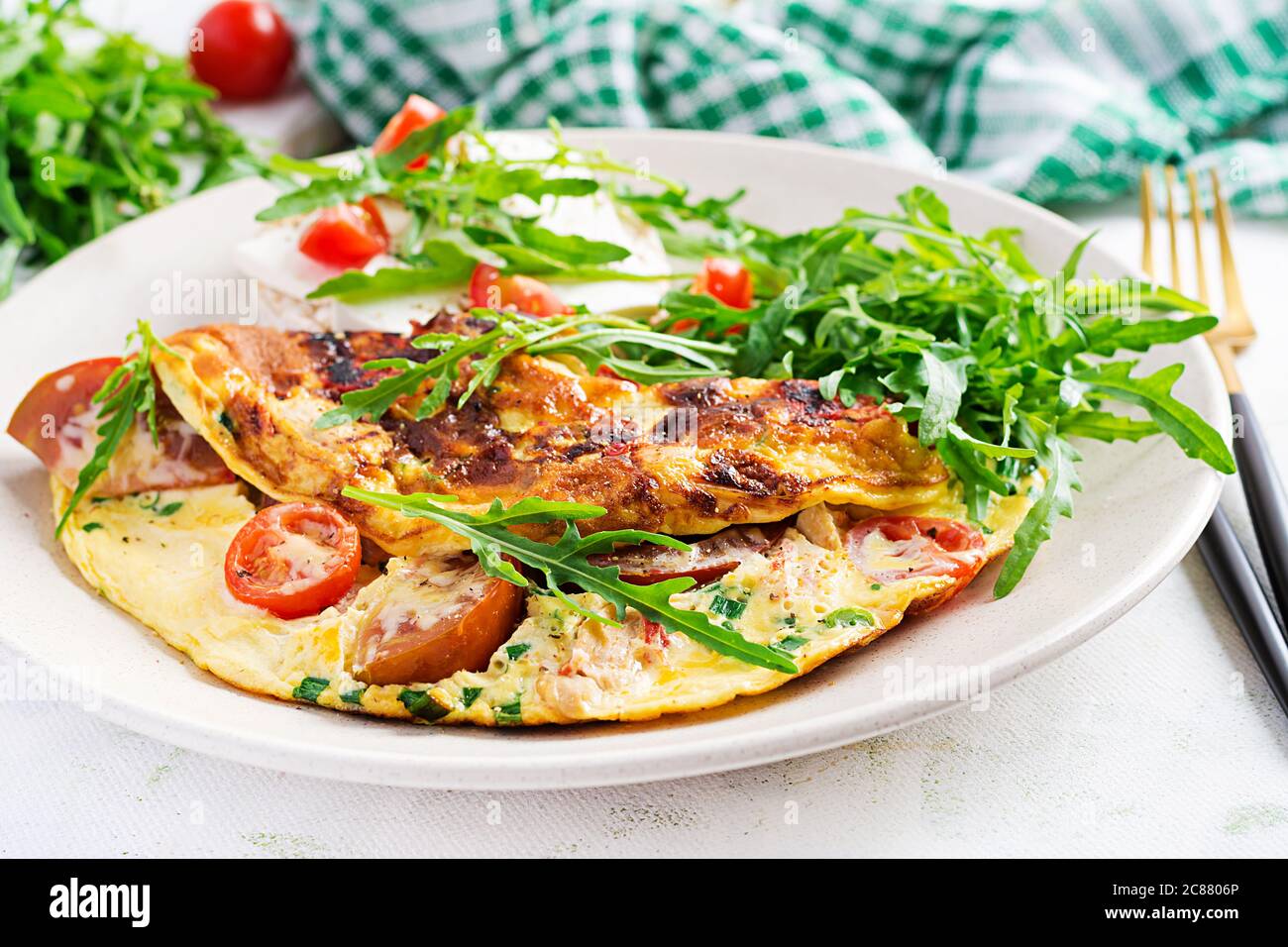 Omelette with tomatoes, cheese and green herbs on plate. Frittata ...