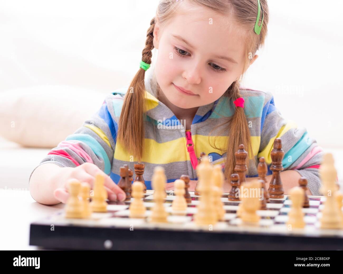 Cute little girl playing chess at home Stock Photo - Alamy