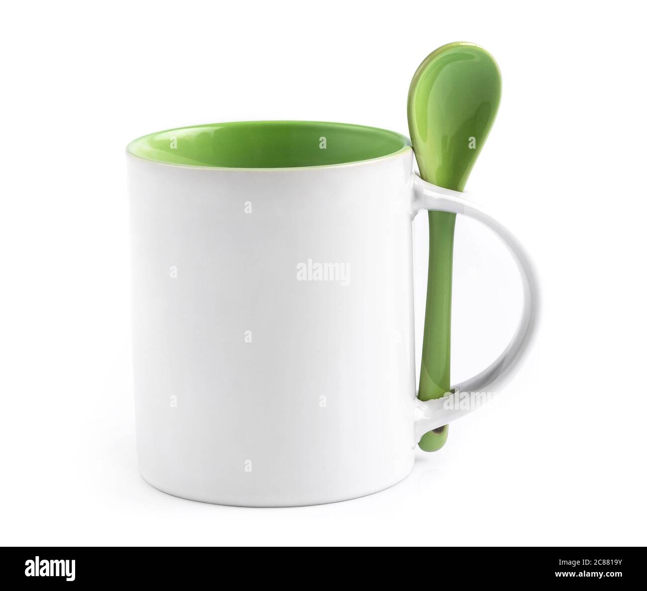 White cup mug with green inside and orange ceramic spoon standing on ...