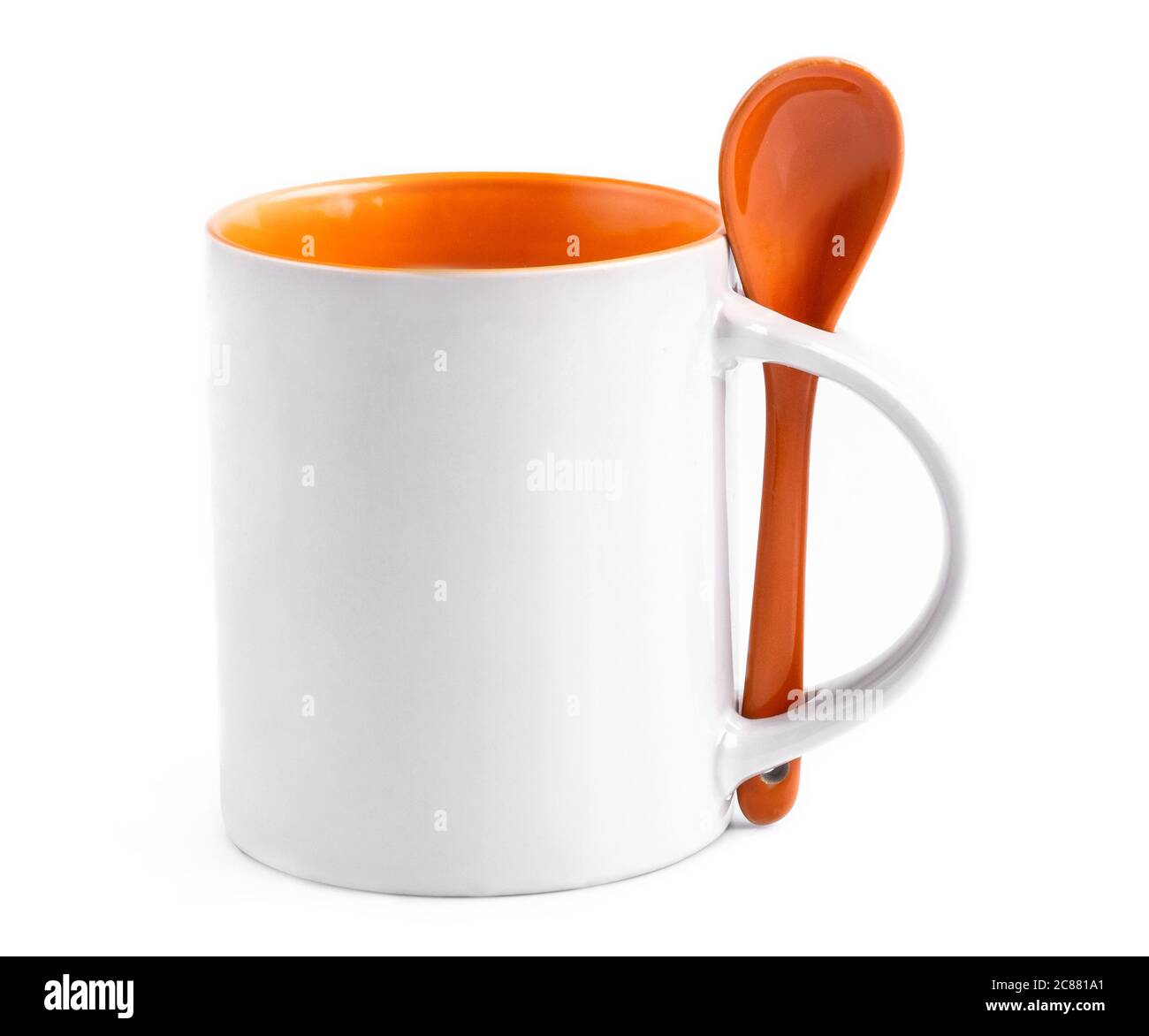 White cup mug with orange inside and orange ceramic spoon standing on ...