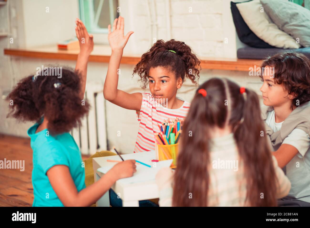Children rising their hands during the art class Stock Photo - Alamy