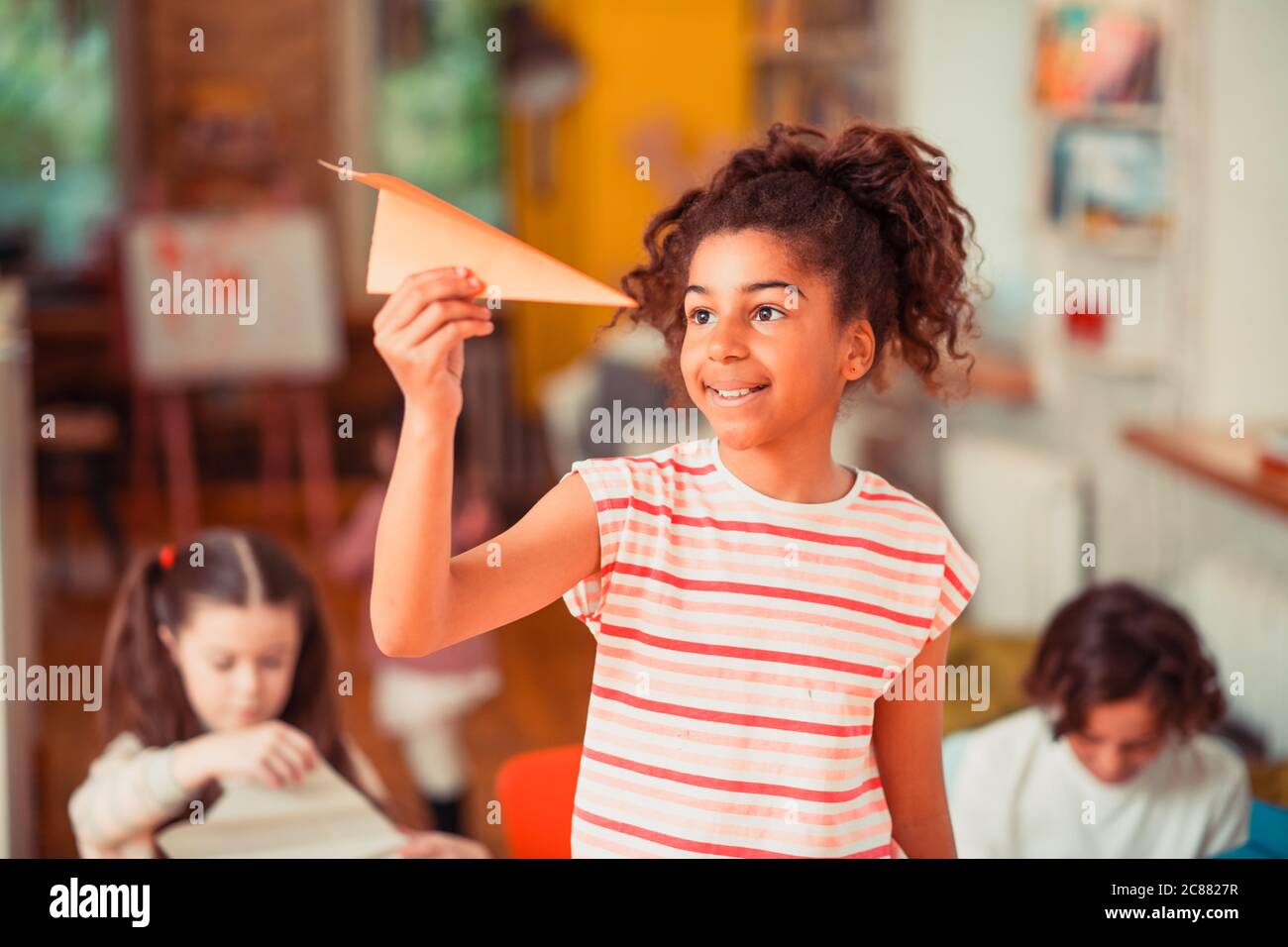 Smiling girl enjoying her origami paper plain Stock Photo - Alamy