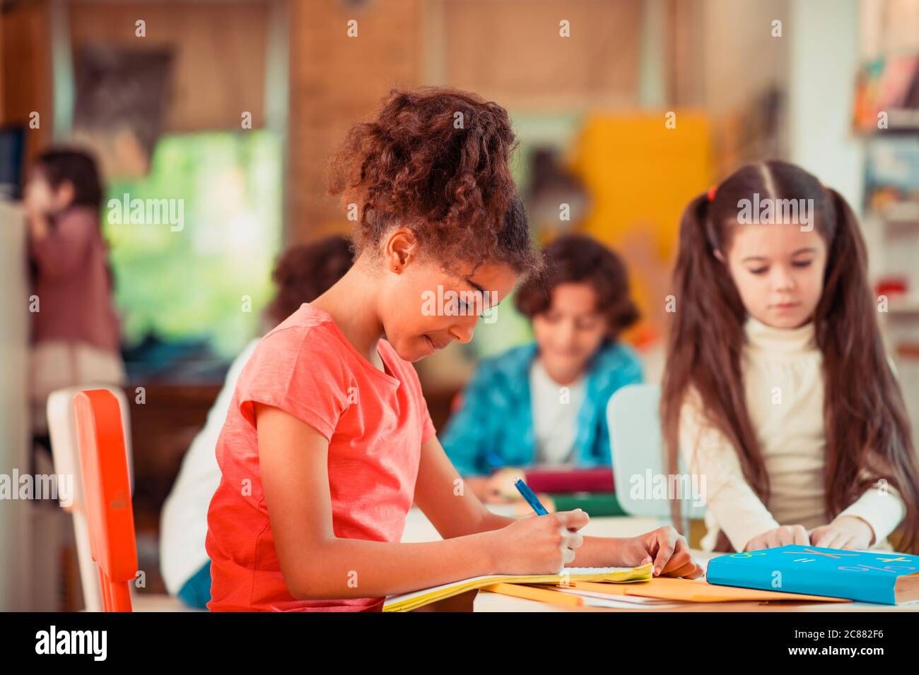Concentrated girl working on her school assignment Stock Photo - Alamy