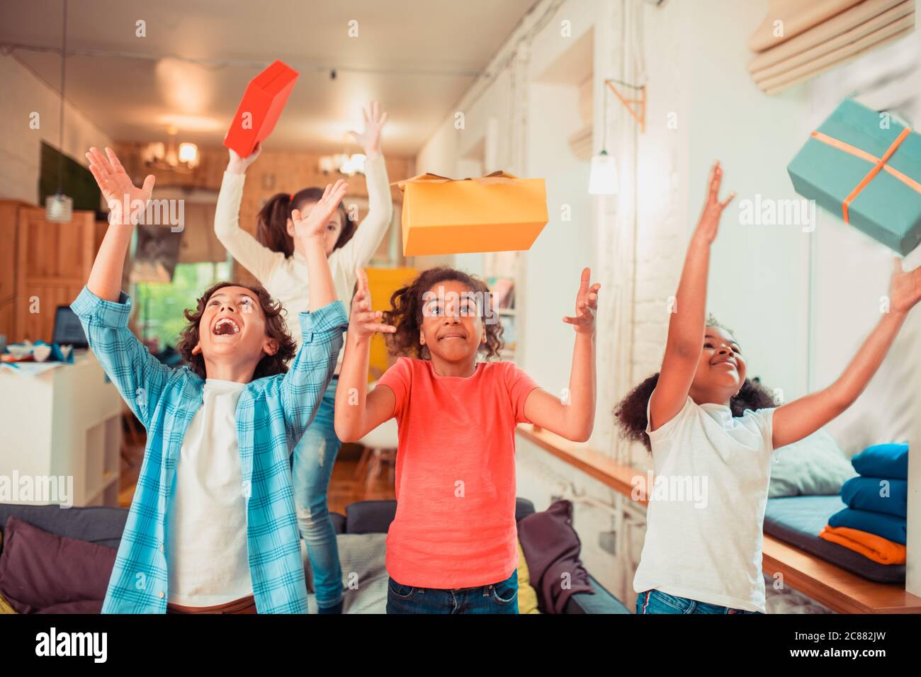 Joyful and active kids throwing gift boxes Stock Photo - Alamy