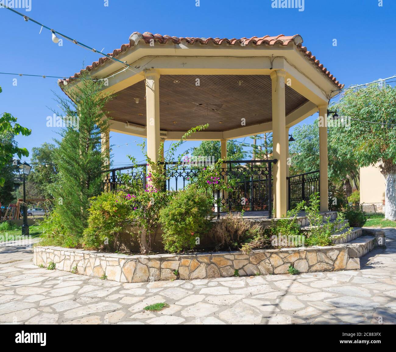 yellow gazebo, arbour with flowers and tree at church garden courtyard ...