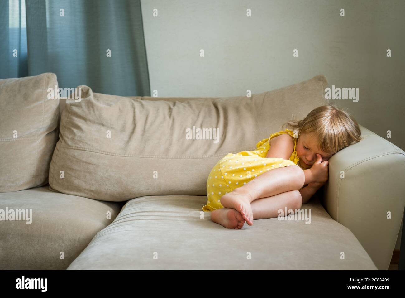 Young cute girl in a yellow dress is lying on the sofa curl up Stock ...