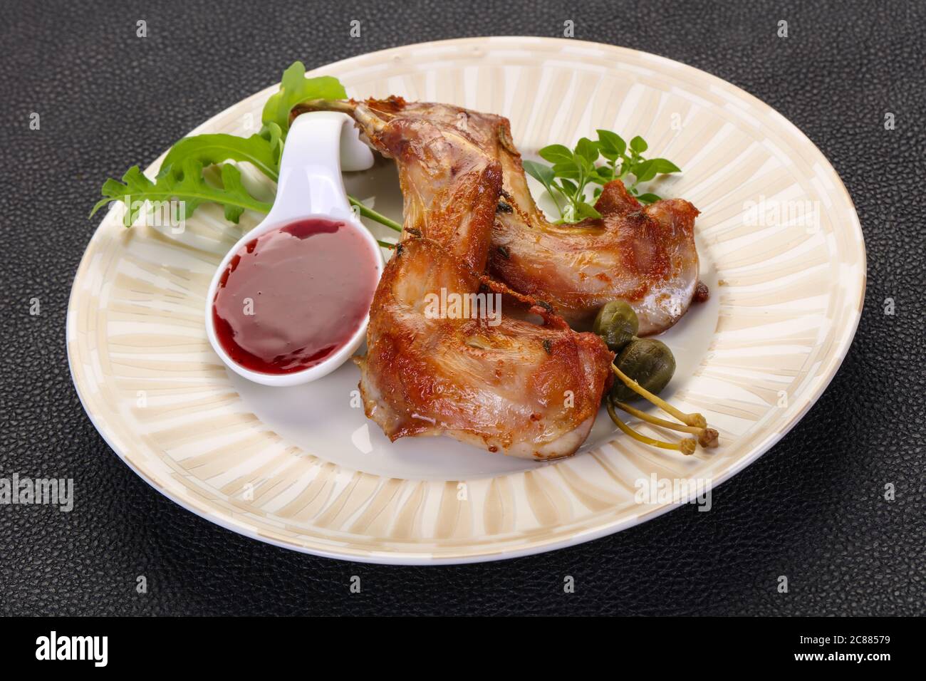 Roasted rabbit legs with cowberry sauce Stock Photo - Alamy