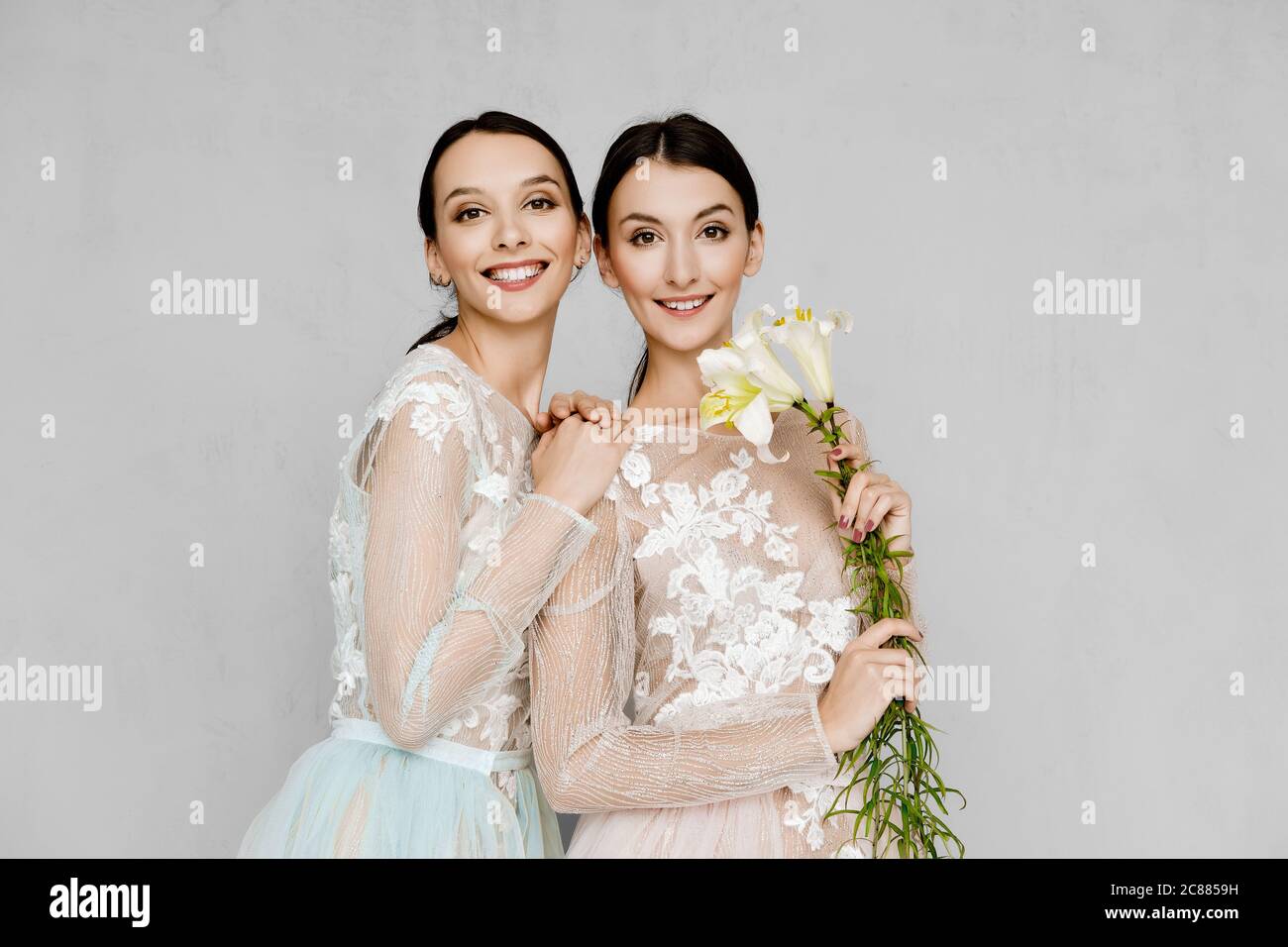Two beautiful girls in transparent tulle dresses with lace posing in ...