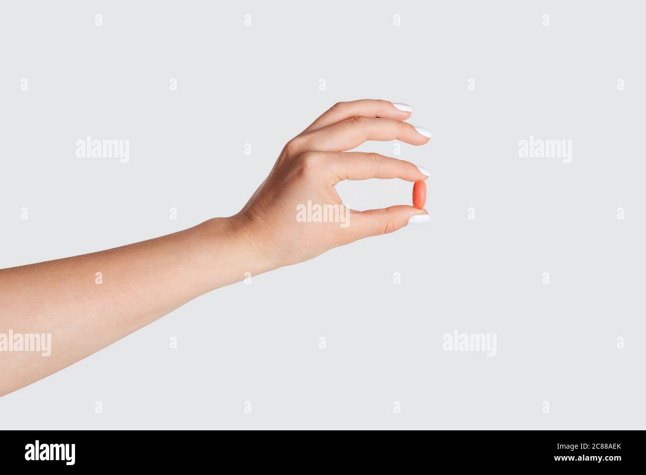 Closeup of female hand holding red pill on white background Stock Photo ...