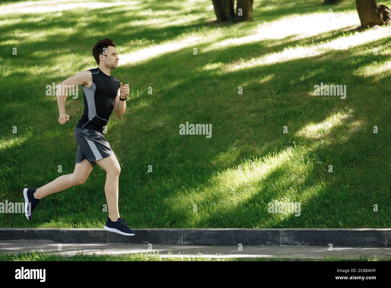 Sportsman in park. Guy in sportswear with sneakers and fitness tracker ...