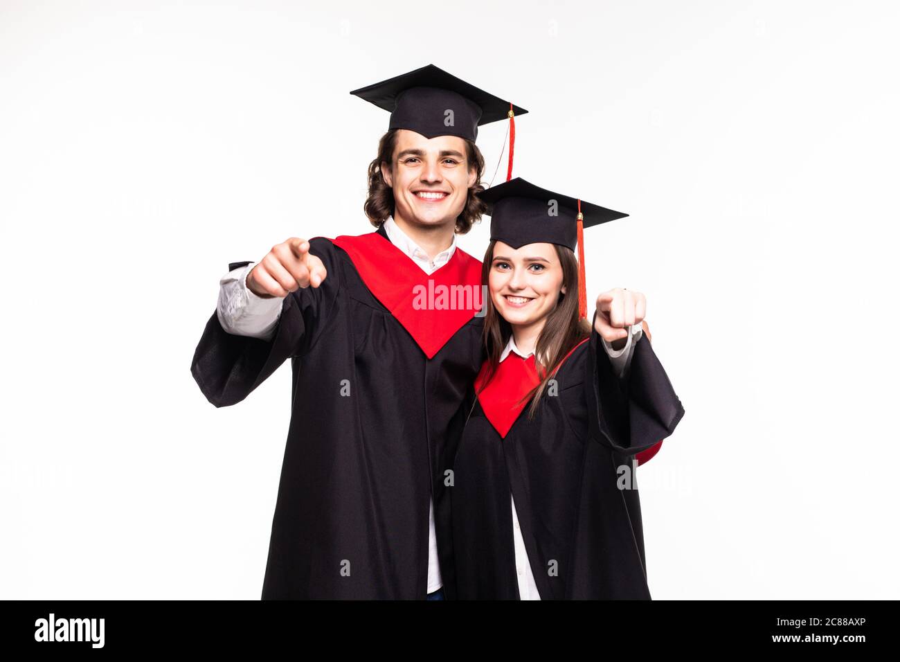 Two graduate couple pointed on camera isolated on white background ...