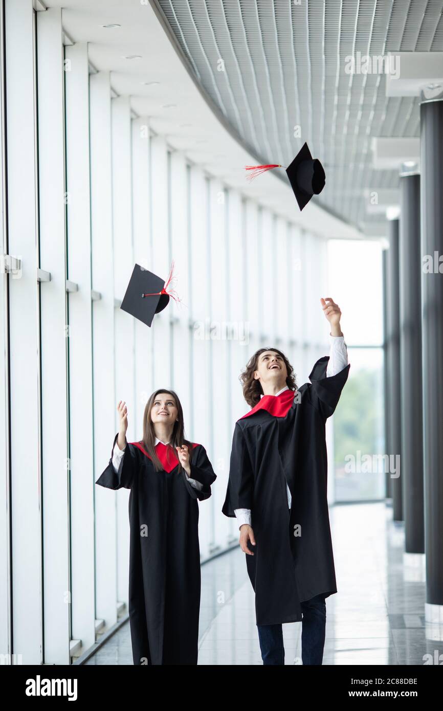 Man and woman graduates throwing graduation hats in the air, happy ...