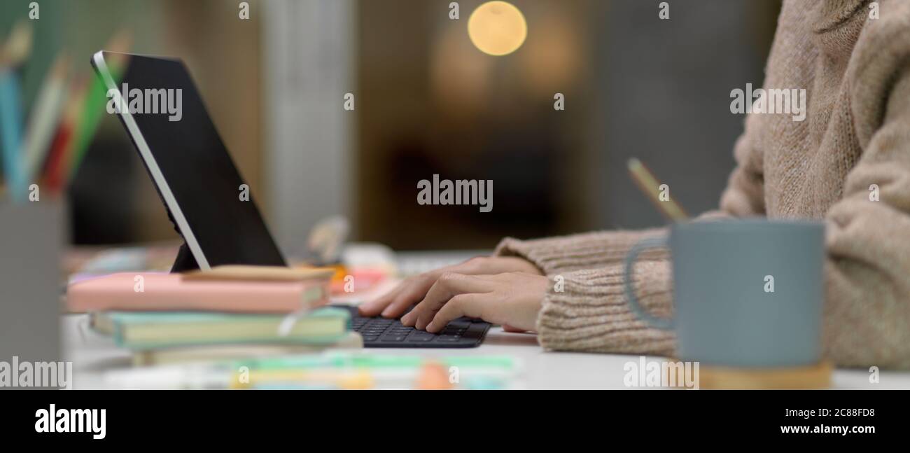 Side view of female student doing assignment with digital tablet and ...