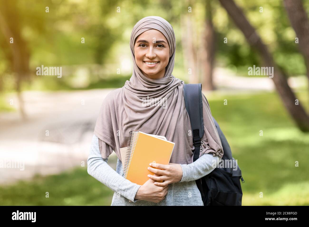 Pretty arab girl student walking by park after school Stock Photo - Alamy