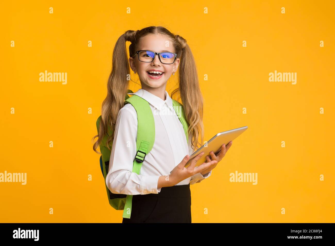 Happy Schoolgirl Holding Digital Tablet Posing Over Yellow Studio ...