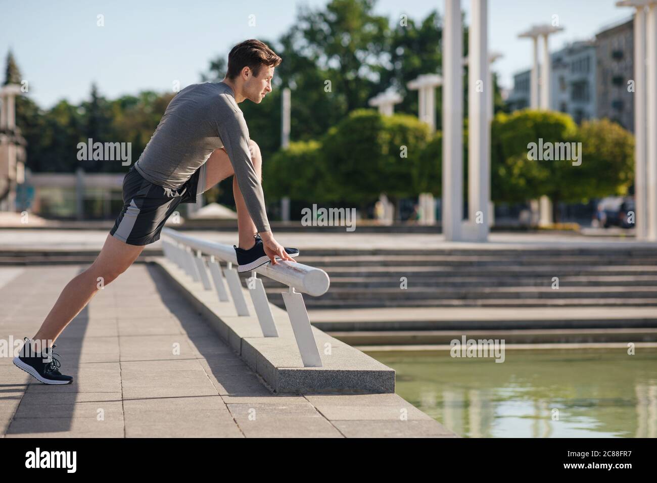 Morning stretching. Guy puts his foot on railing and does exercises ...