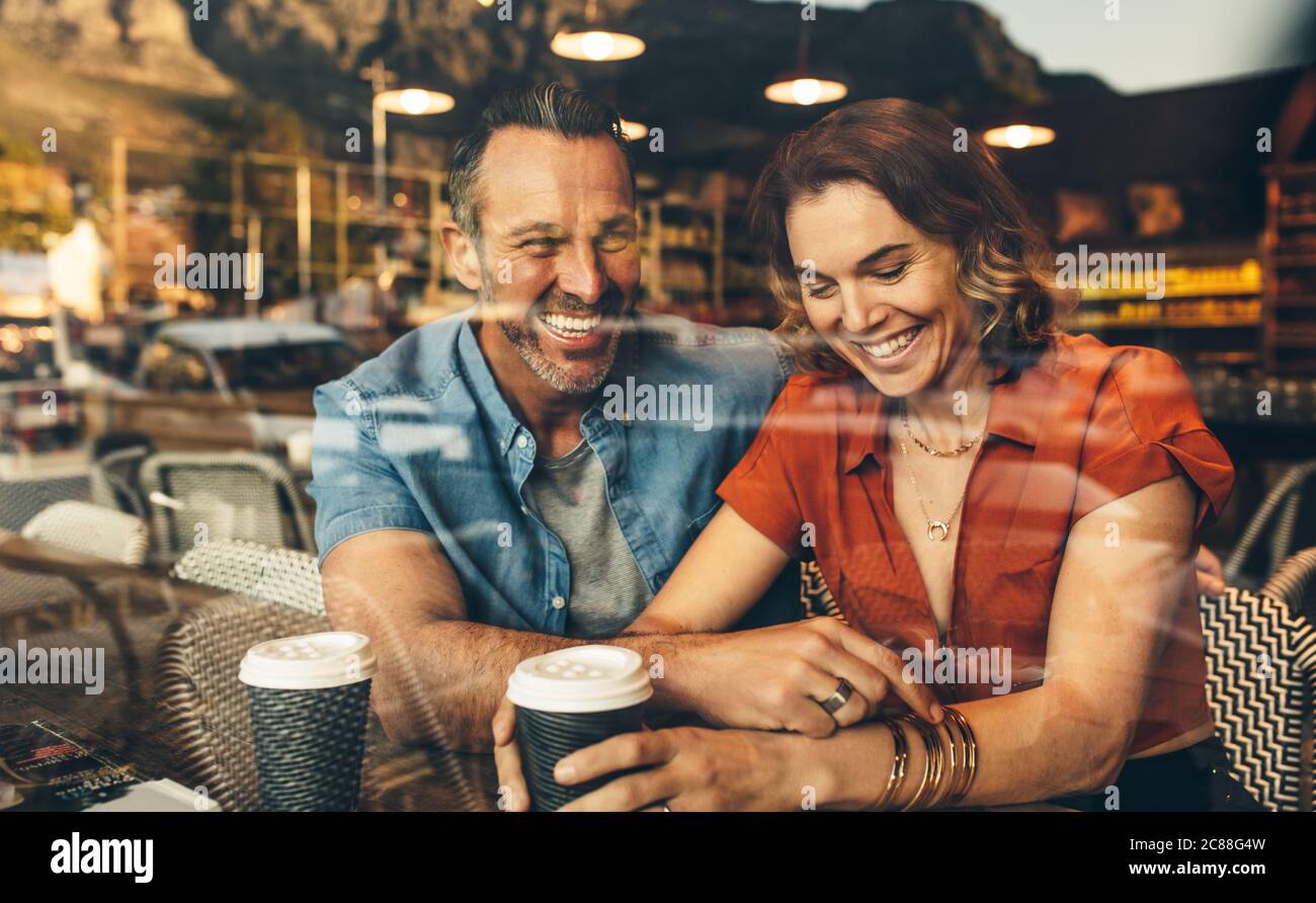 Couple sitting inside a cafe and smiling. Couple on a date at a local ...