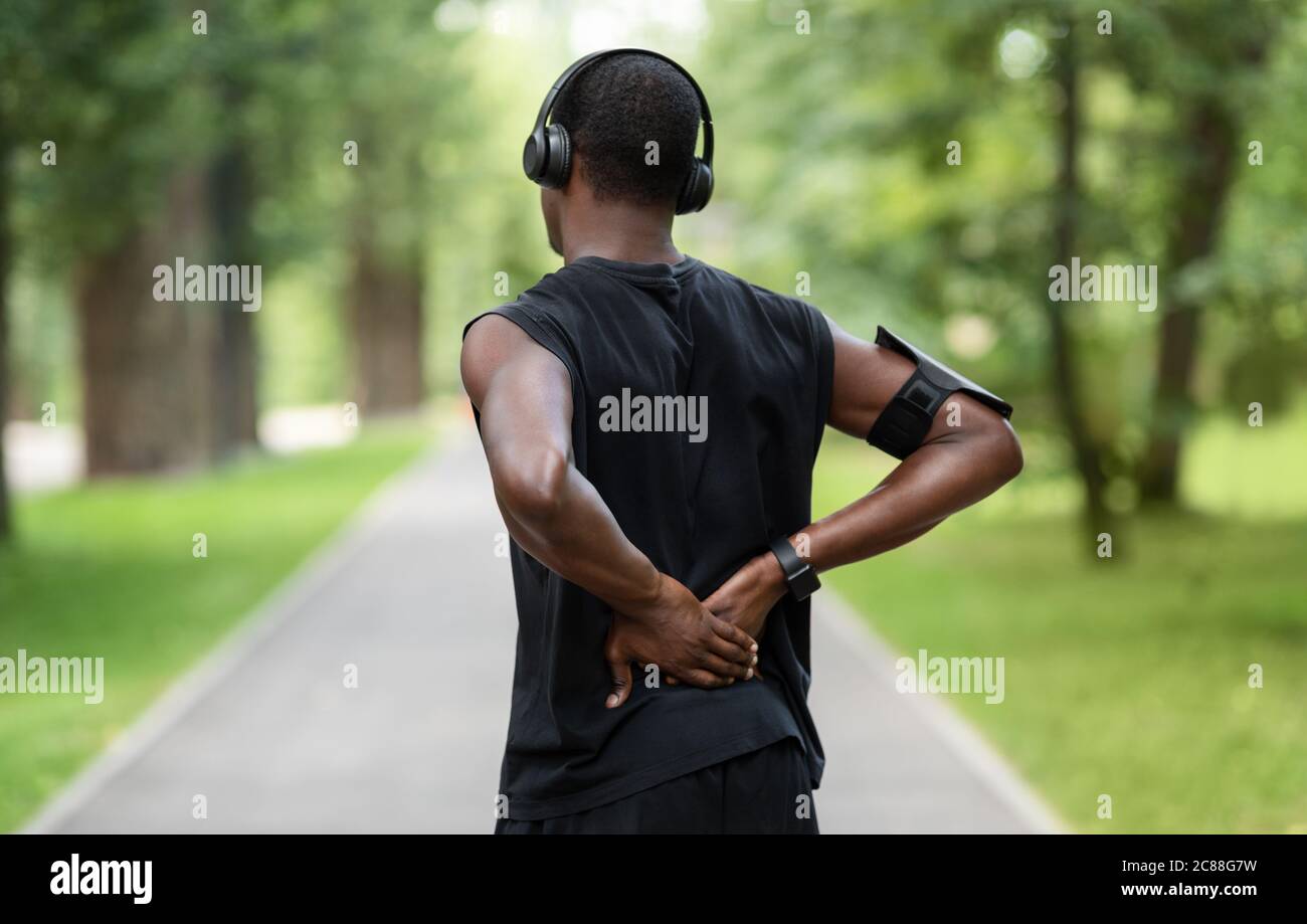 Back view of black man in sportswear touching injured back Stock Photo ...