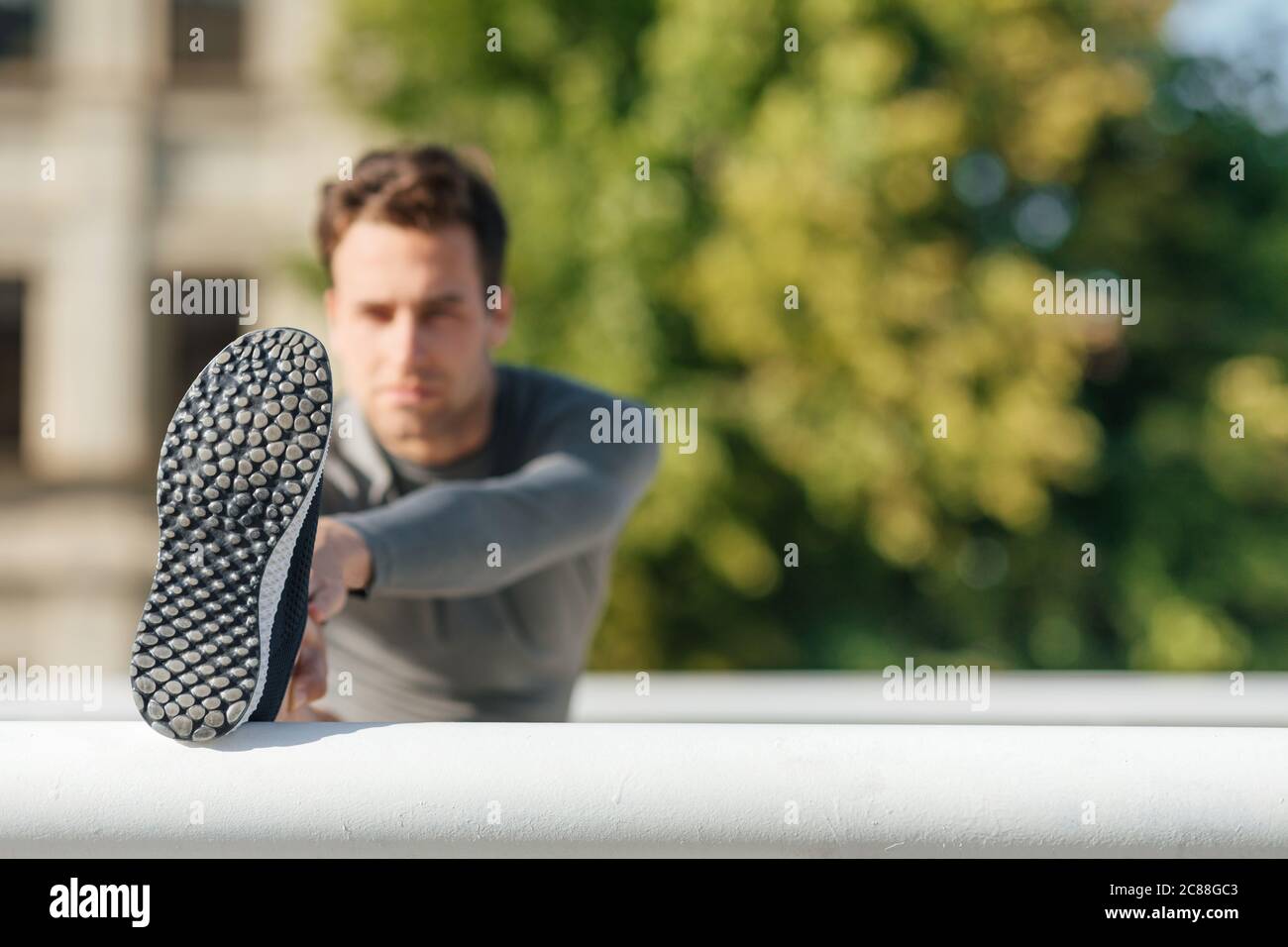 Muscular young man in sportswear lifts his leg on railing Stock Photo ...