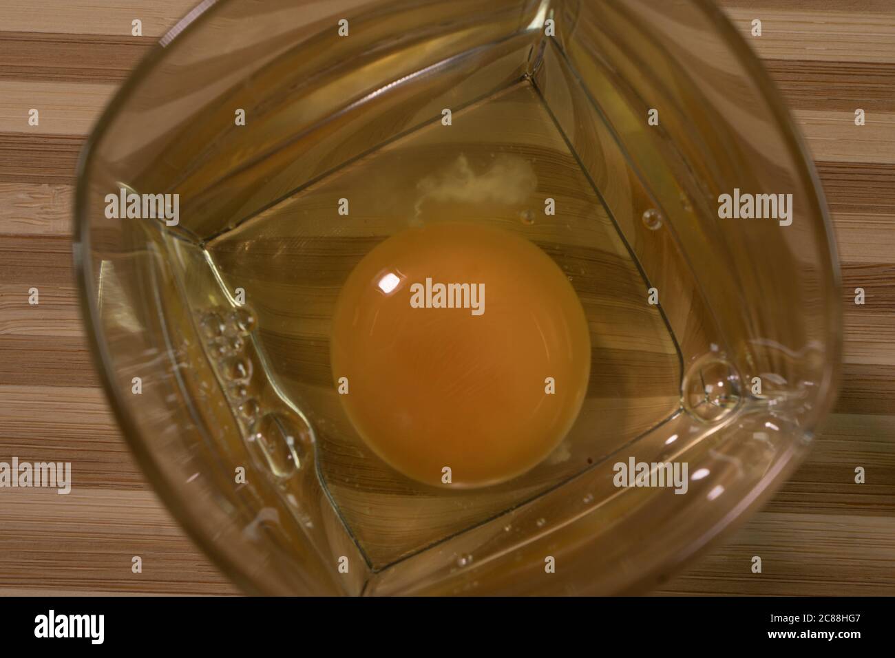 Raw egg in a glass beaker. On a wooden board Stock Photo - Alamy