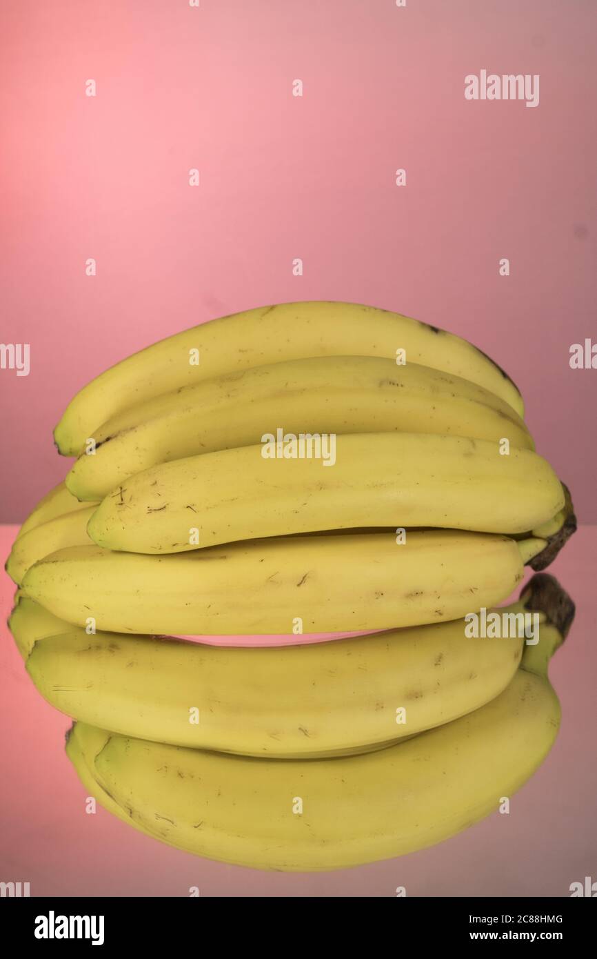 A bunch of bananas on mirroring table on mirror red background with ...