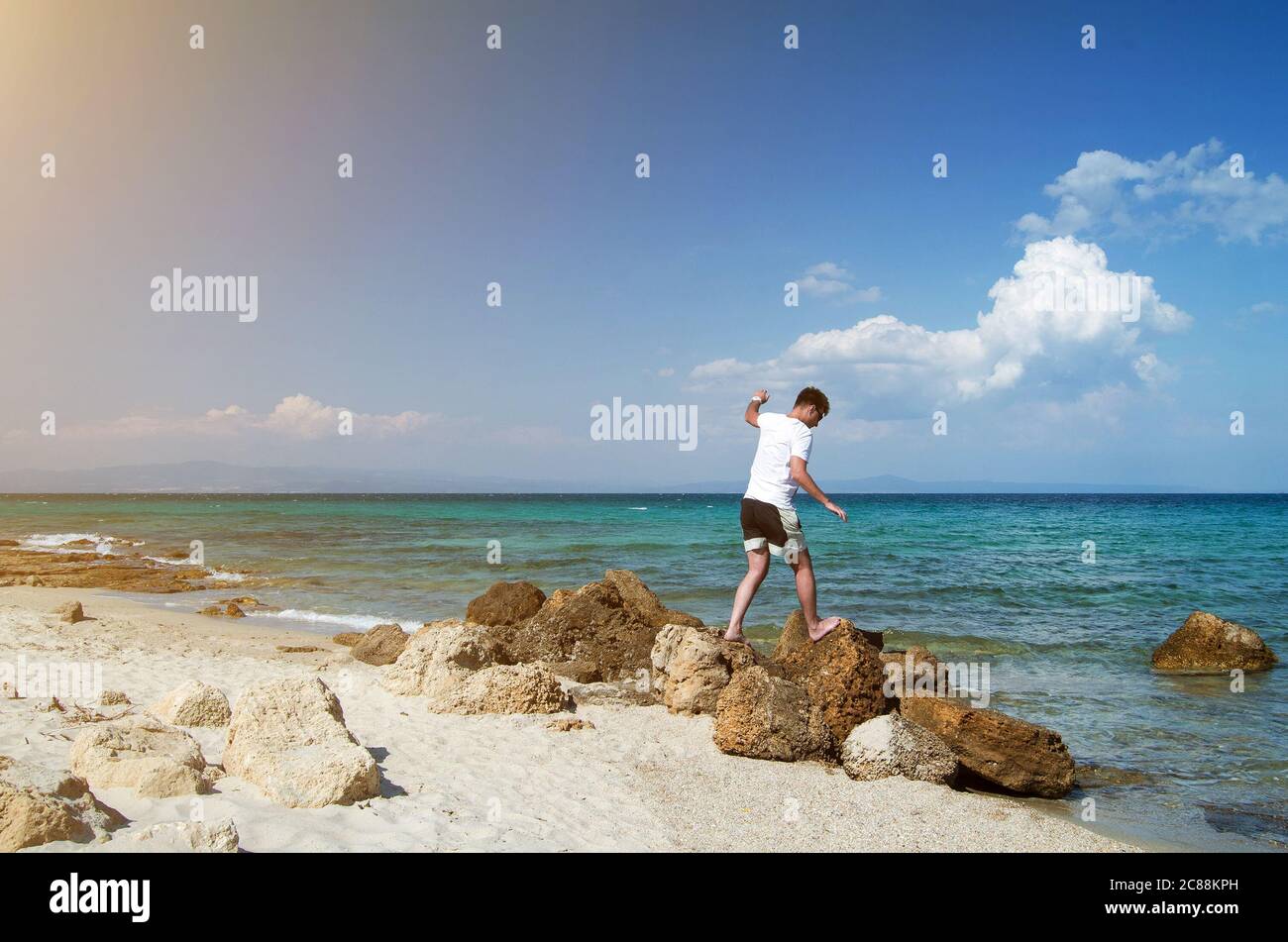 Young man climbing rocks on the beach Stock Photo - Alamy