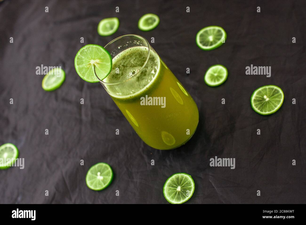 Delicious lime juice with a sliced lime on a black fabric with sliced ...