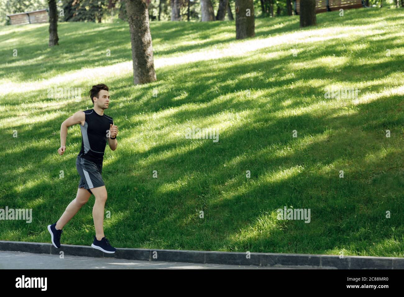 Muscle workout and jogging. Man with fitness tracker runs along track ...
