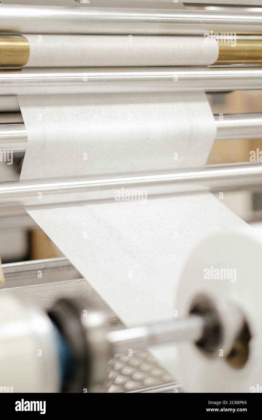 Vertical closeup shot of a roll of paper passing through a printing ...