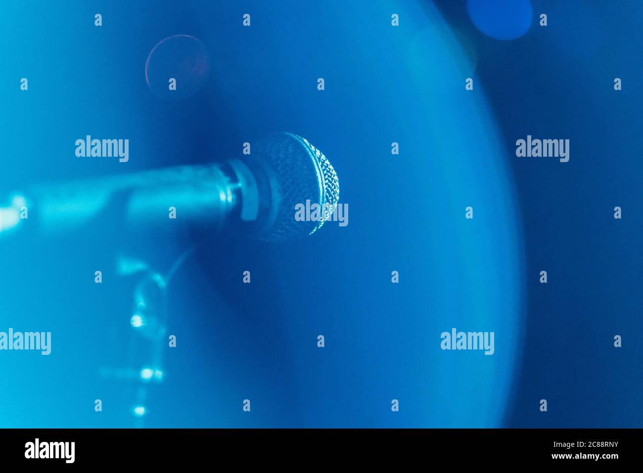 Closeup shot of a gray microphone on a blue background with bokeh ...