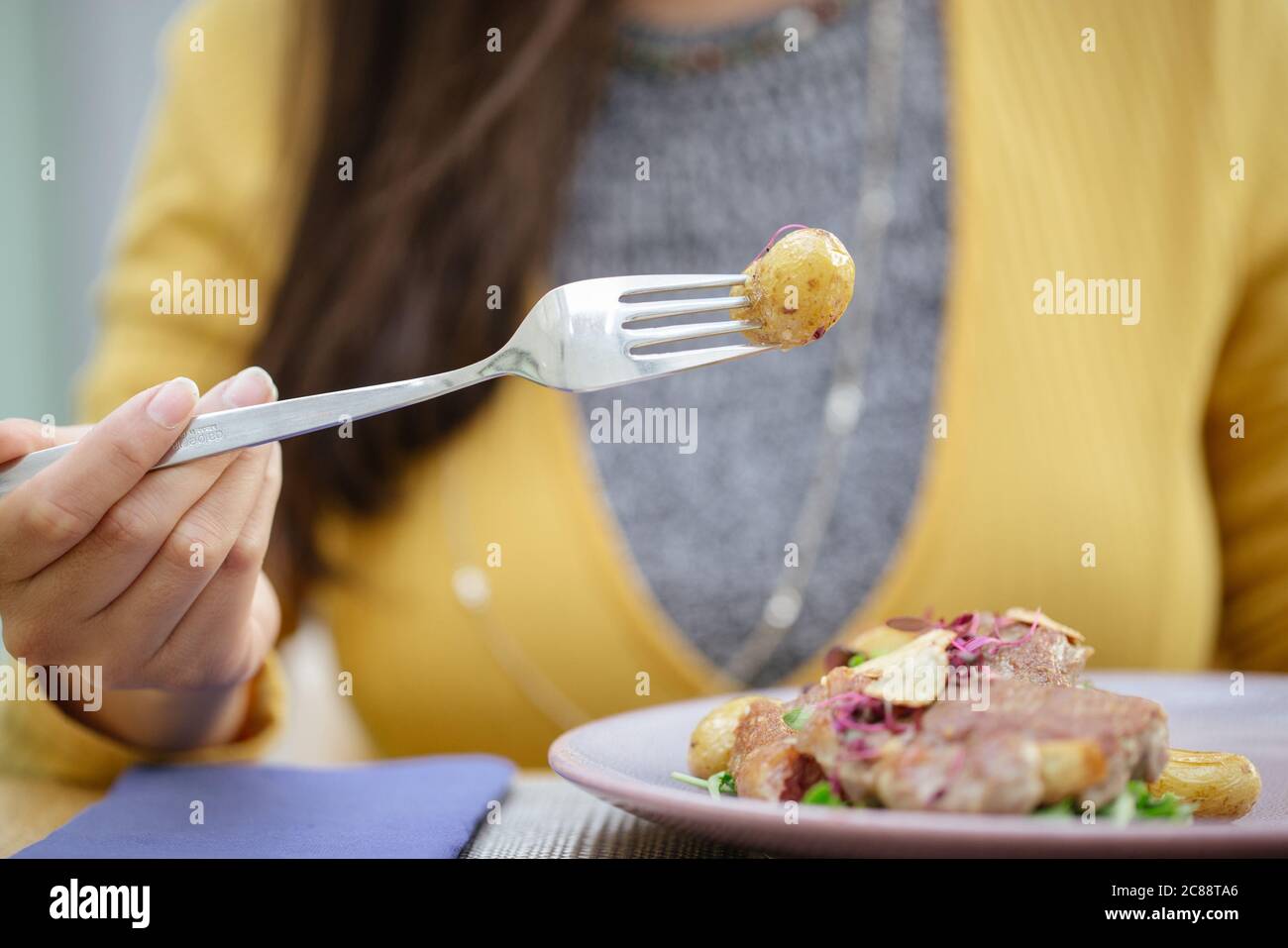 Female eating a steak with fresh small potatoes Stock Photo - Alamy