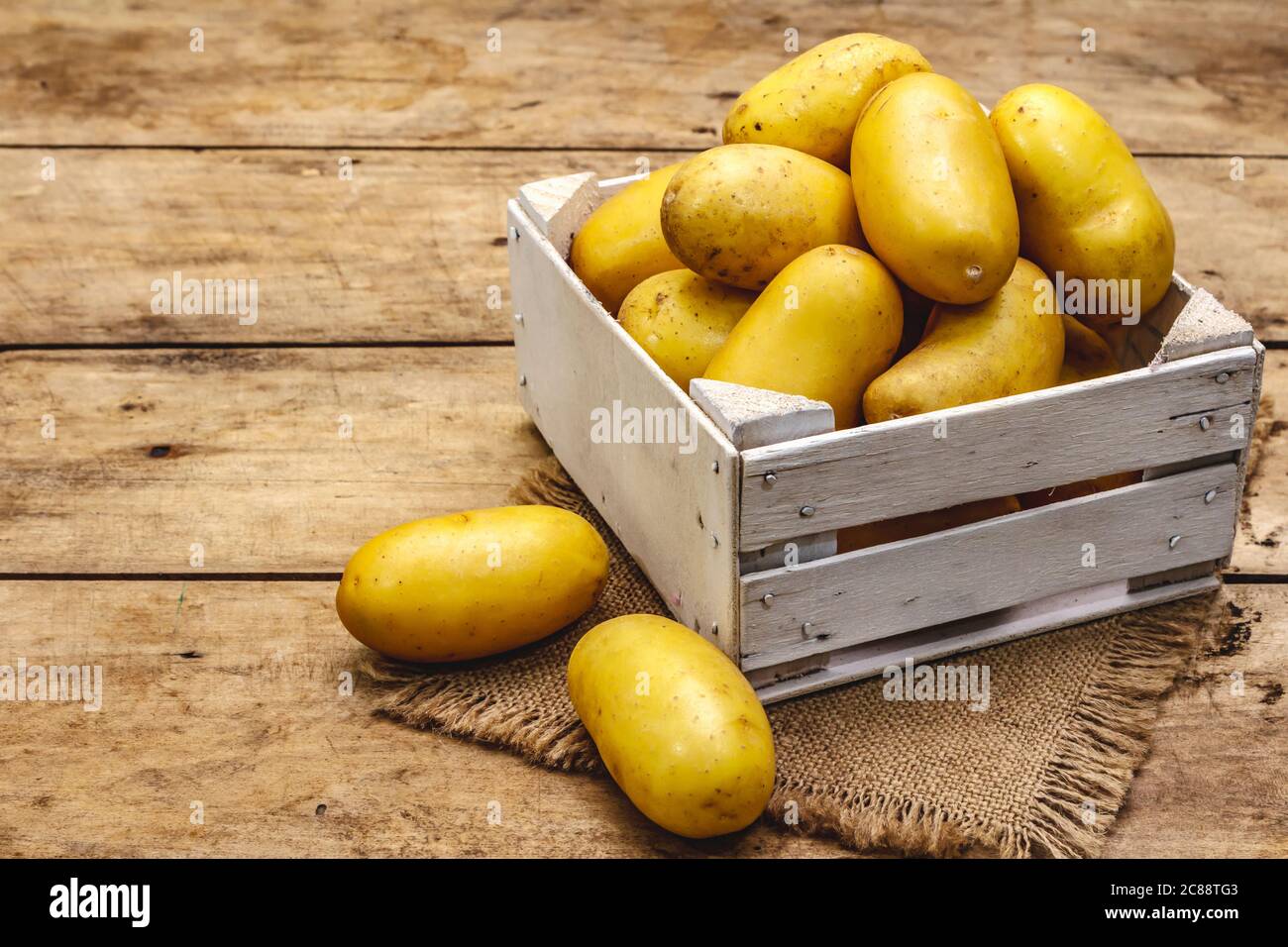 Whole unpeeled raw potatoes in a wooden crate. New harvest, on ...
