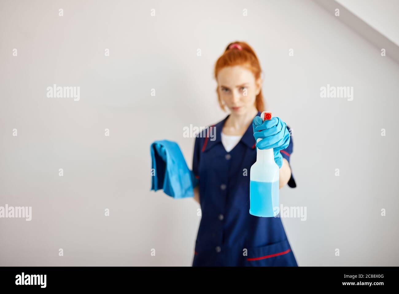 Positive pretty young cleaning lady in blue uniform holds cleaning ...