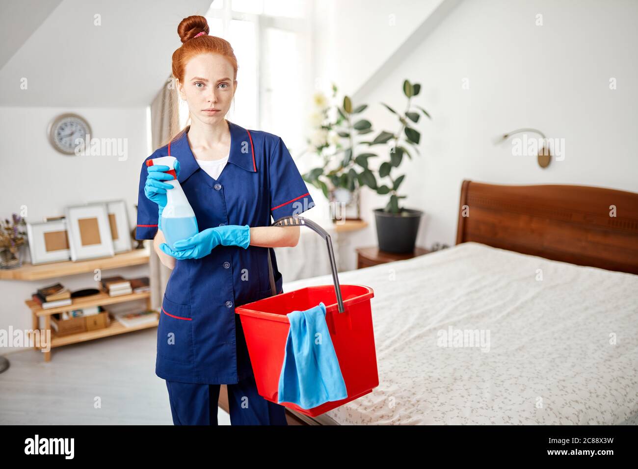 Positive pretty young cleaning lady in blue uniform holds cleaning ...