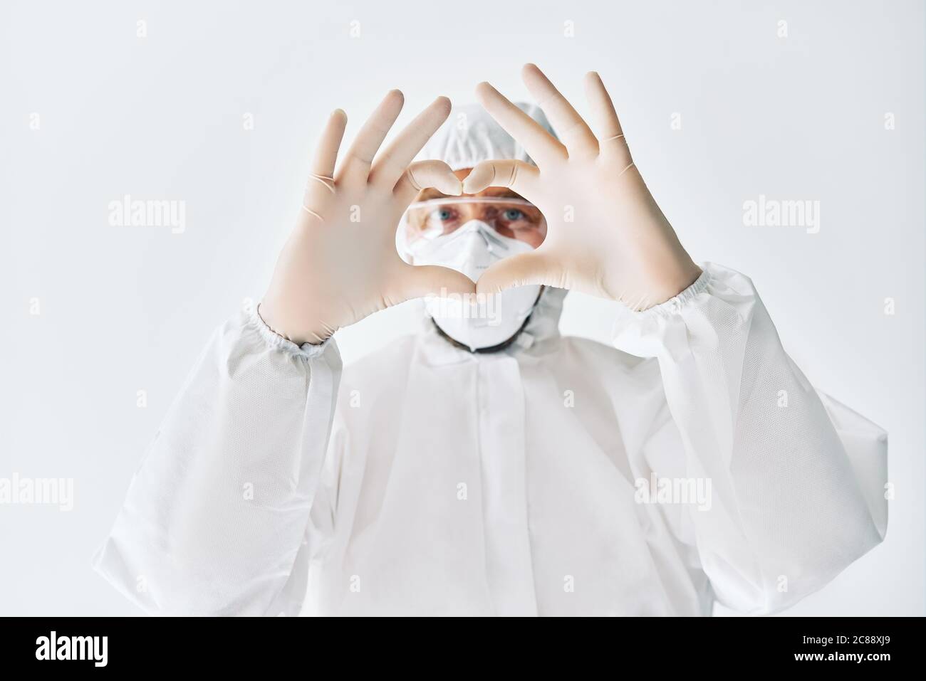 Doctor making heart shape symbol with hands wearing protective medical ...