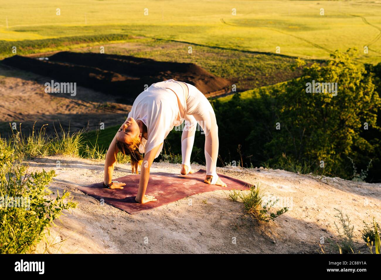Beautiful woman practicing Wheel yoga asana pose on top of rock ...
