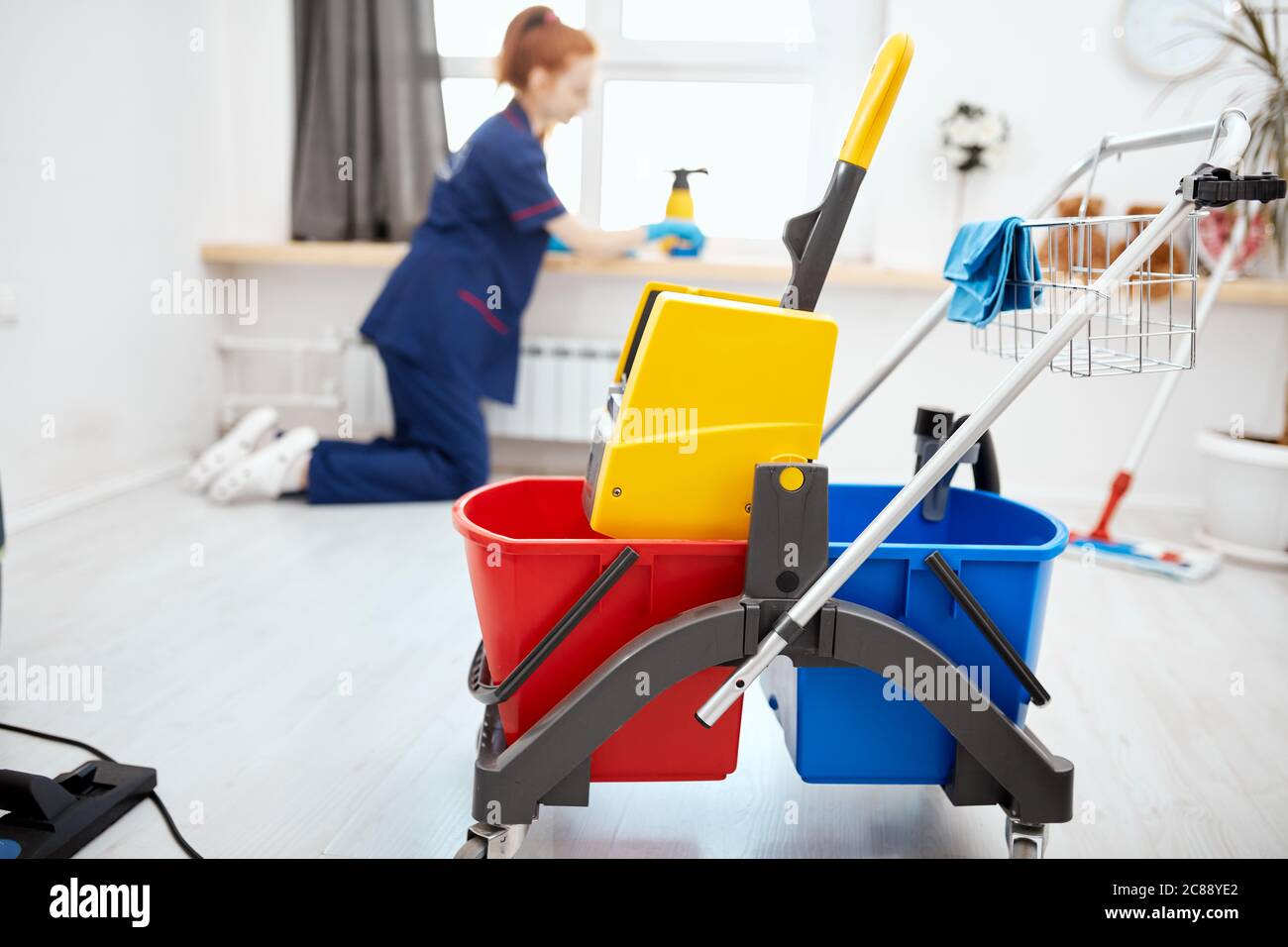 Colorful cleaning tools cart close up with blurred image of young red ...