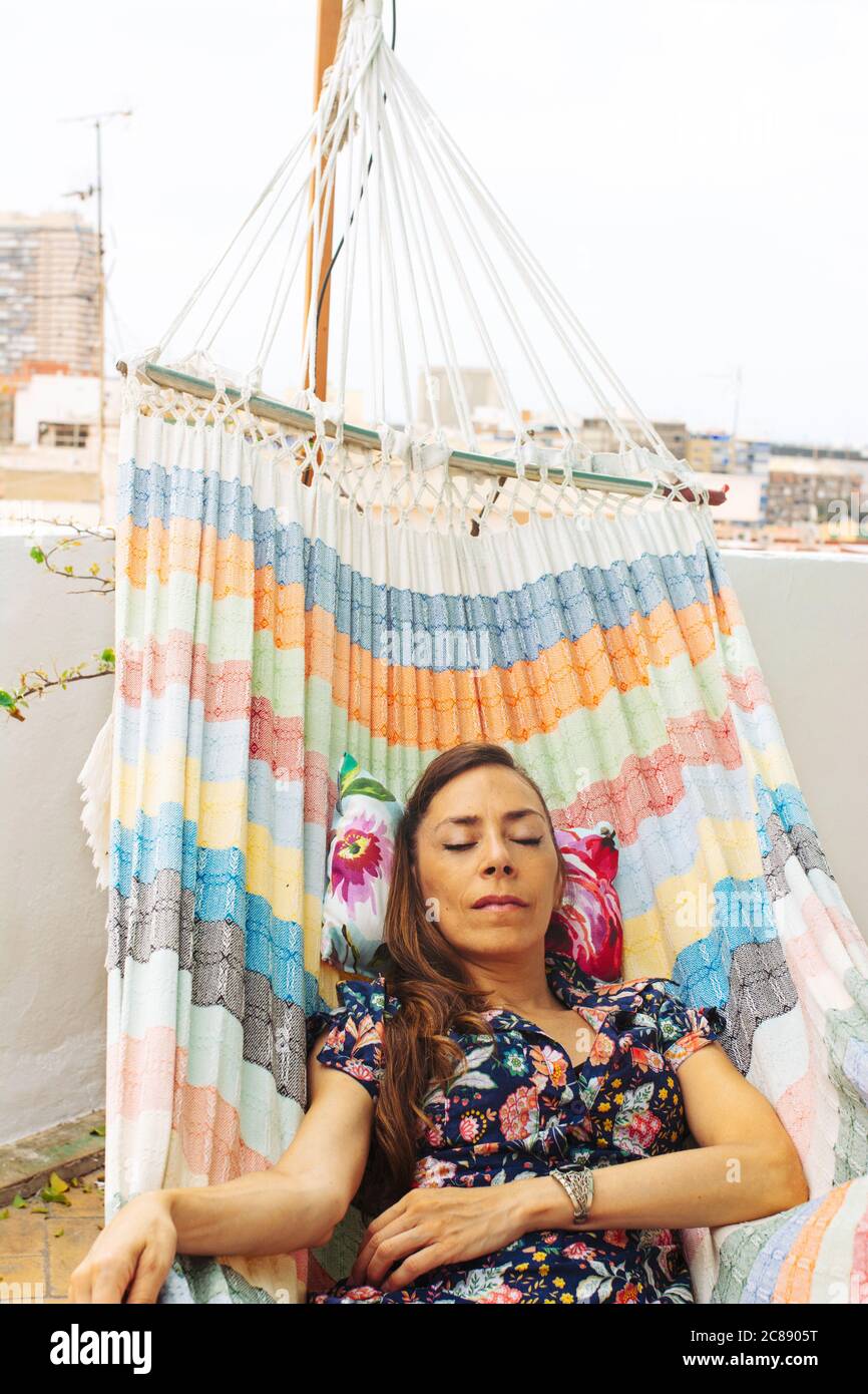 Beautiful relaxed woman, napping on hammock, in a floral dress ...