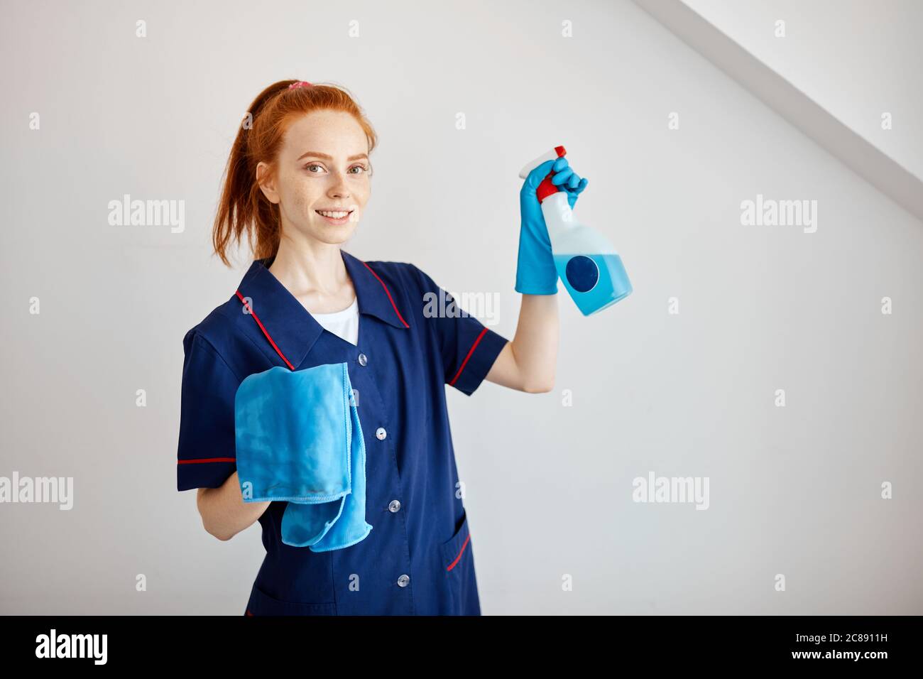 hotel maid dressed in professional blue uniform holding wiper and ...