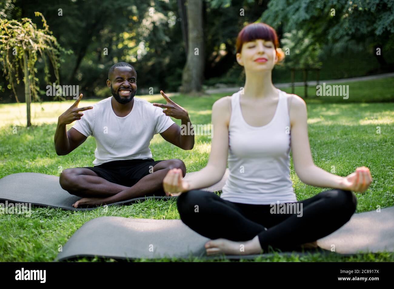 Multiethnic young couple relaxing while sitting in lotus position on ...