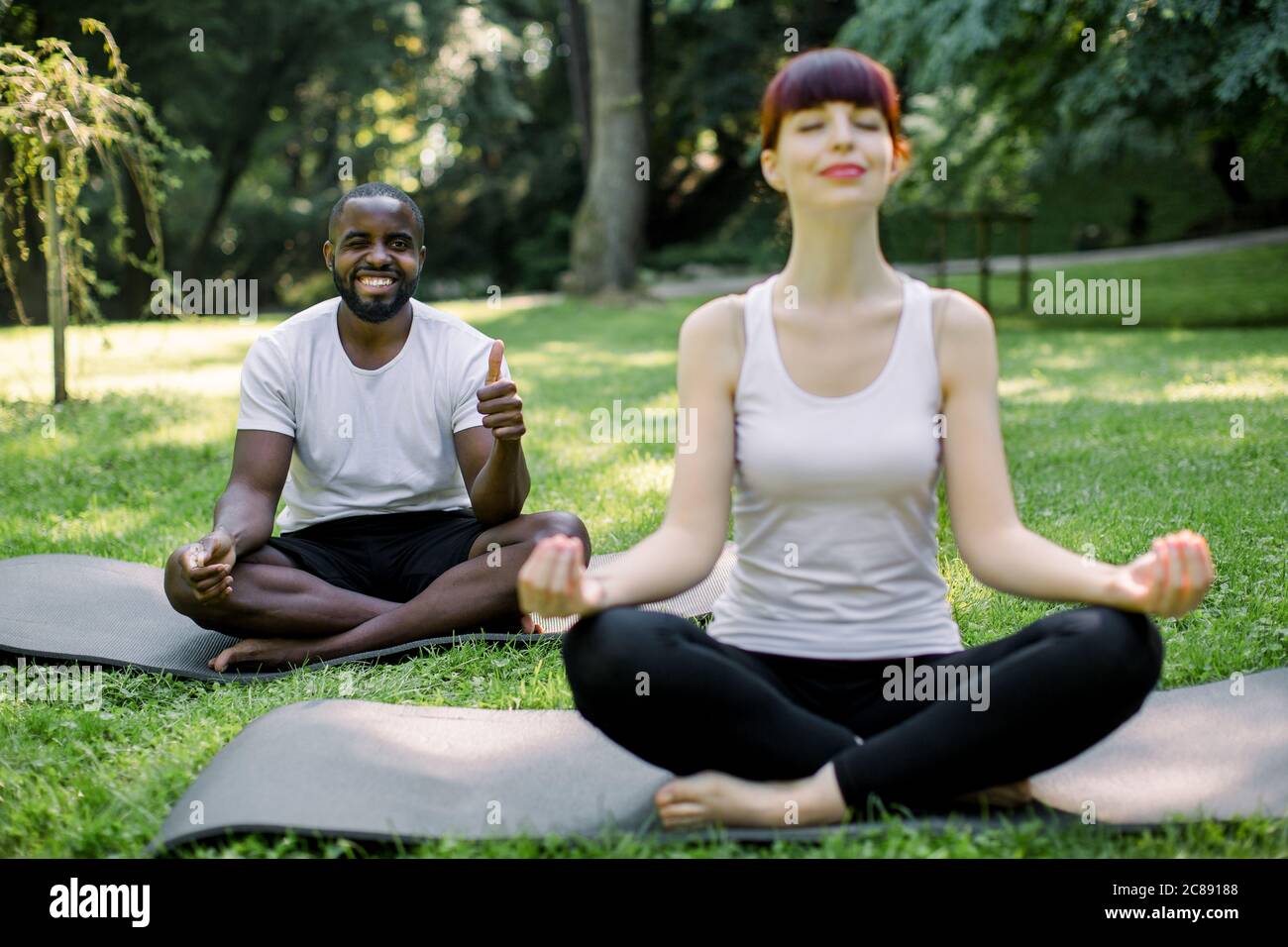 Multiethnic young couple relaxing while sitting in lotus position on ...