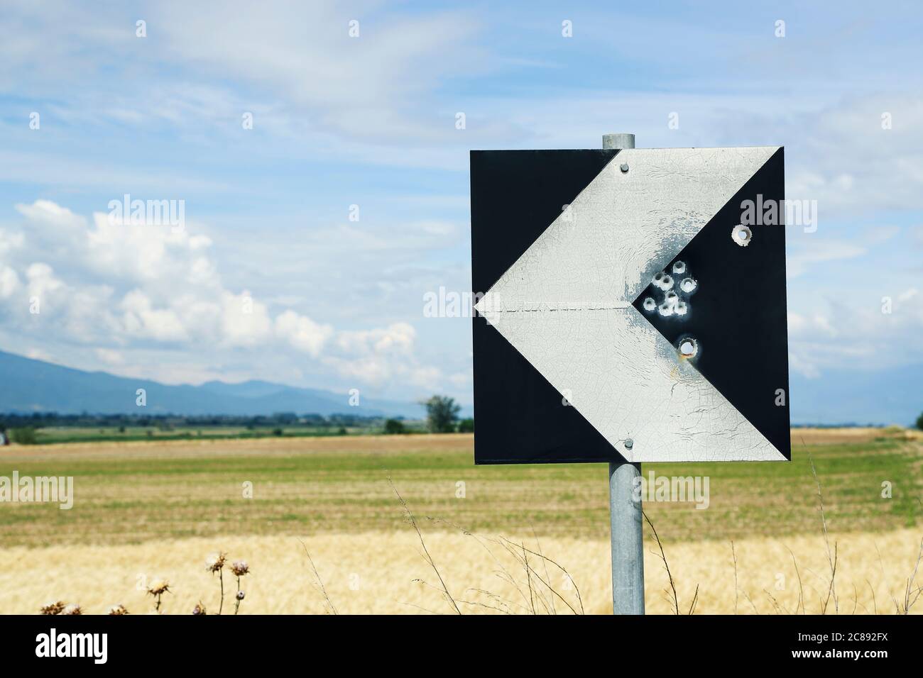 bullet holes on weathered road sign with arrow Stock Photo - Alamy