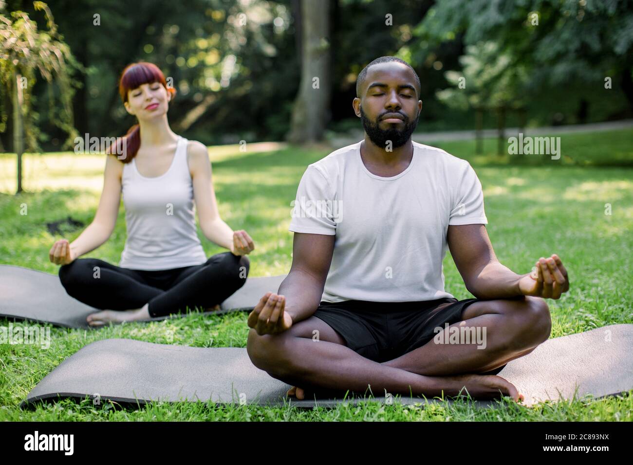 Close-up of multiracial couple taking a rest in the park, practising ...