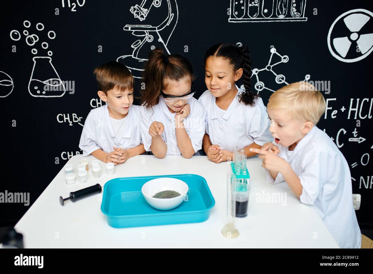 Group of multiracial diverse kids in scientist white clothes doing ...