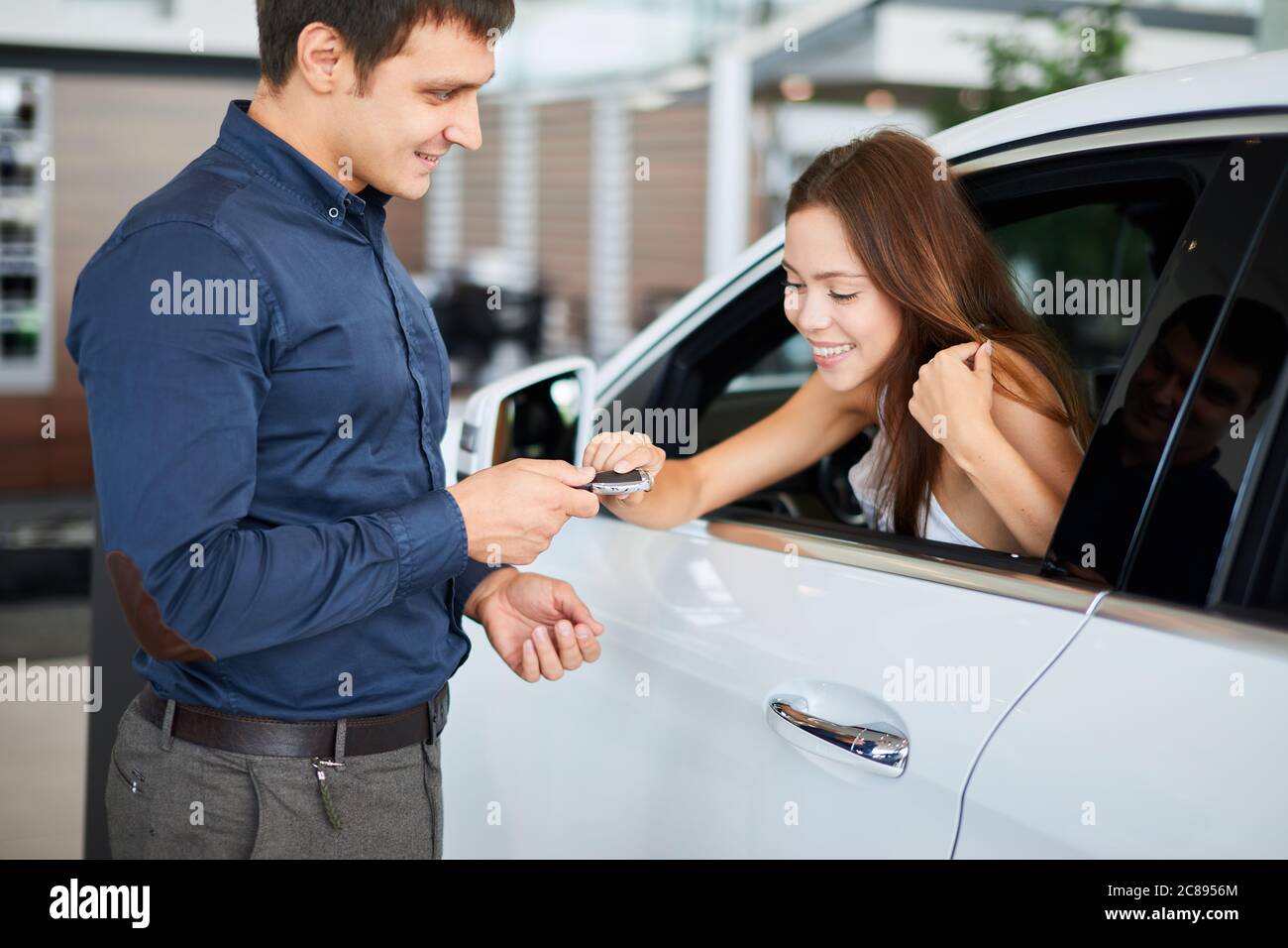 Image of loving husband giving key from a new car to his happy wife, a ...