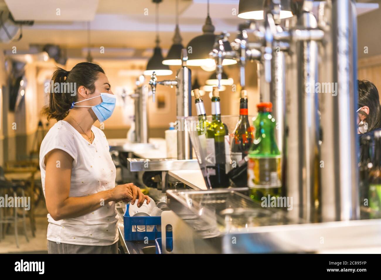 Shallow focus shot of a Hispanic female waitress in a face mask working ...