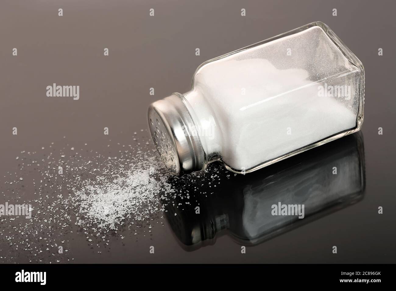 full salt shaker on black surface Stock Photo - Alamy