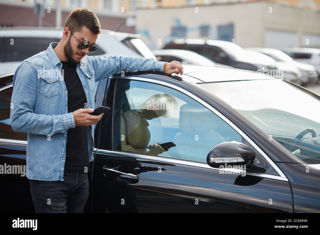 serious guy leaning on the car and texting a message. close up photo ...